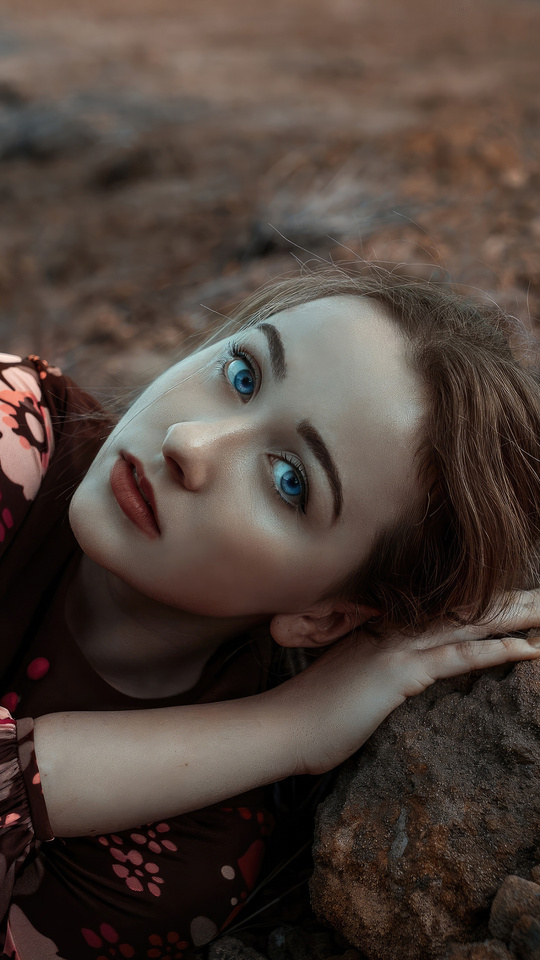 540x960 Blue Eyes Girl Lying On Beach Rock Wallpaper 540x960 Resolution